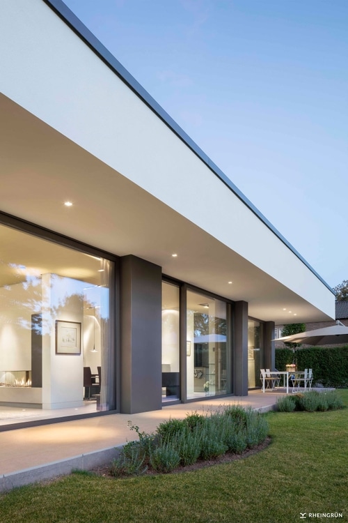 Villa mit Flachdach, großer Rasenfläche und akzentuierter Bepflanzung ...