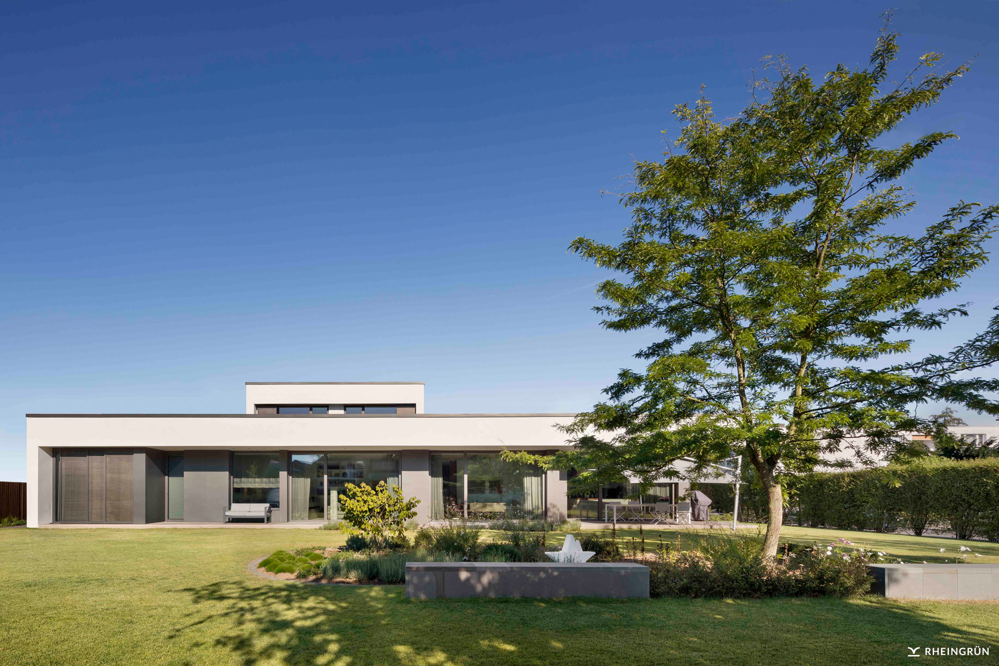 Villa mit Flachdach, großer Rasenfläche und akzentuierter Bepflanzung ...