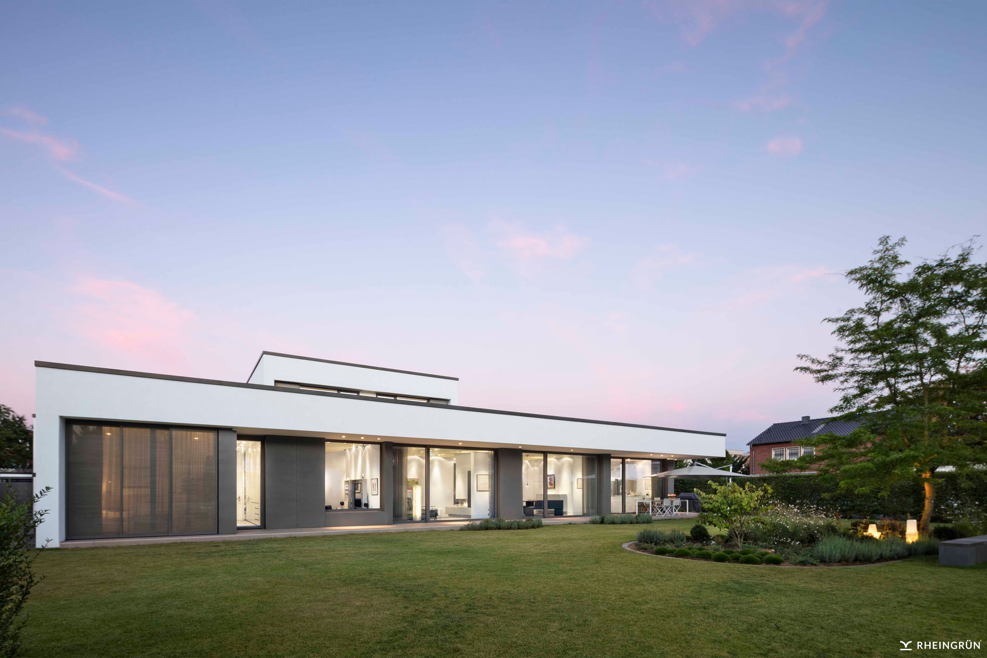 Villa mit Flachdach, großer Rasenfläche und akzentuierter Bepflanzung ...