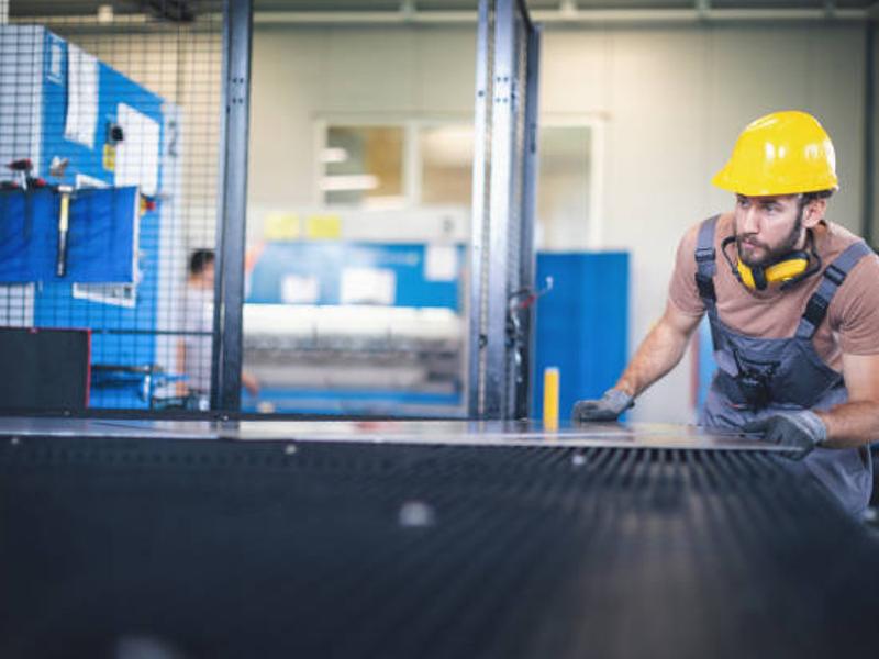 metal sheet worker with safety equipment, checking a metal sheet